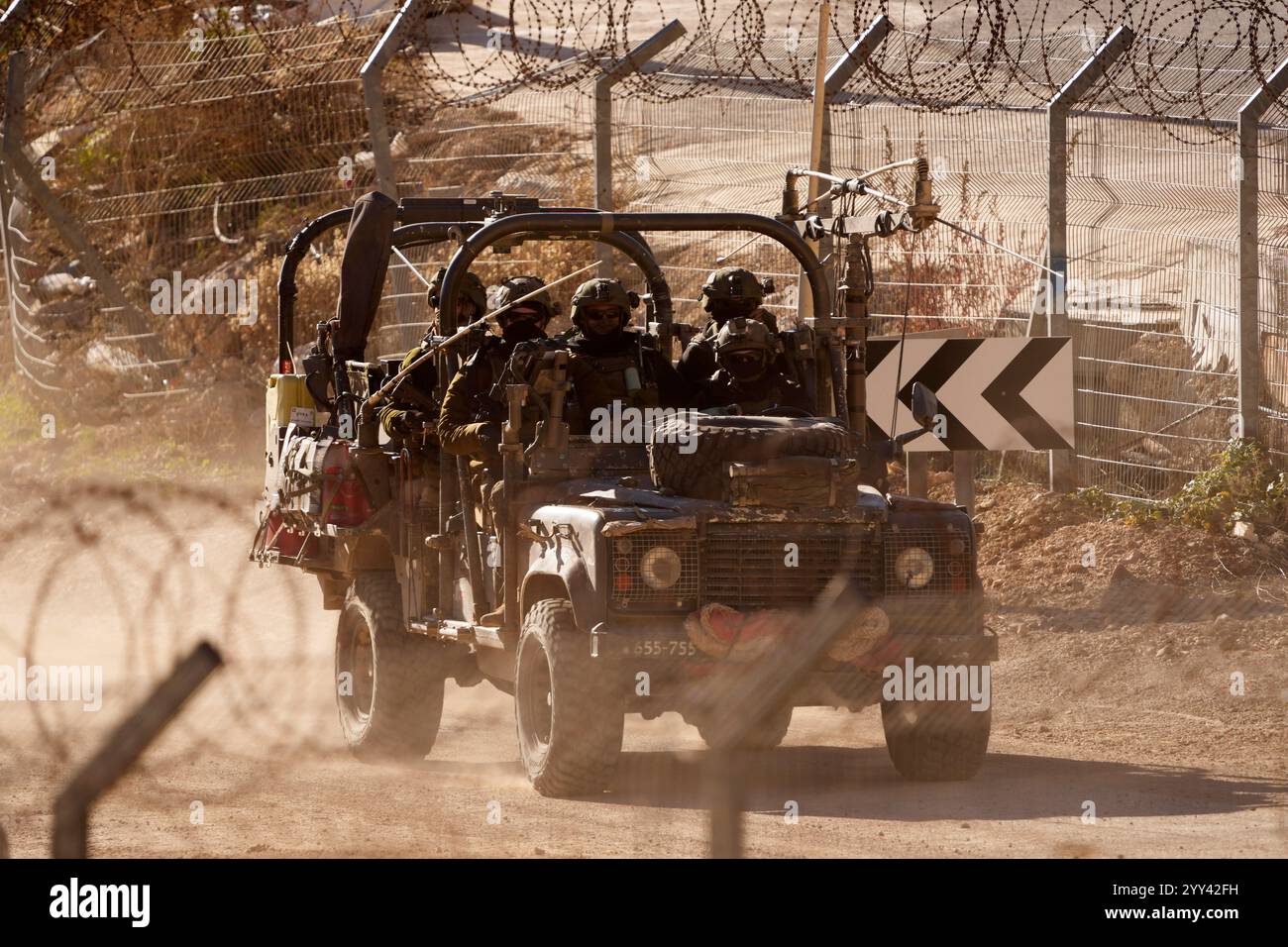 Israeli soldiers drive an armoured vehicle along the security fence ...