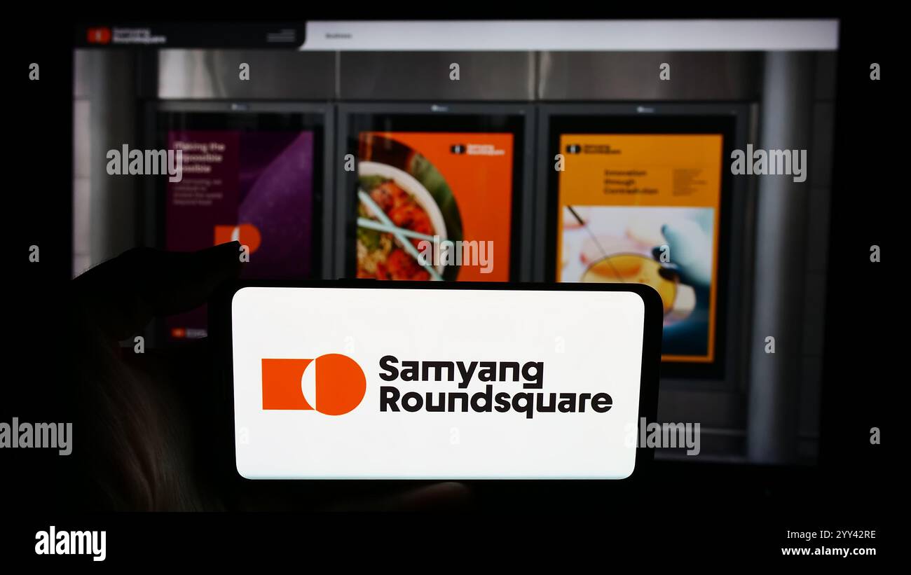 In this photo illustration, a person is holding a cellphone with the logo of South Korean food ...