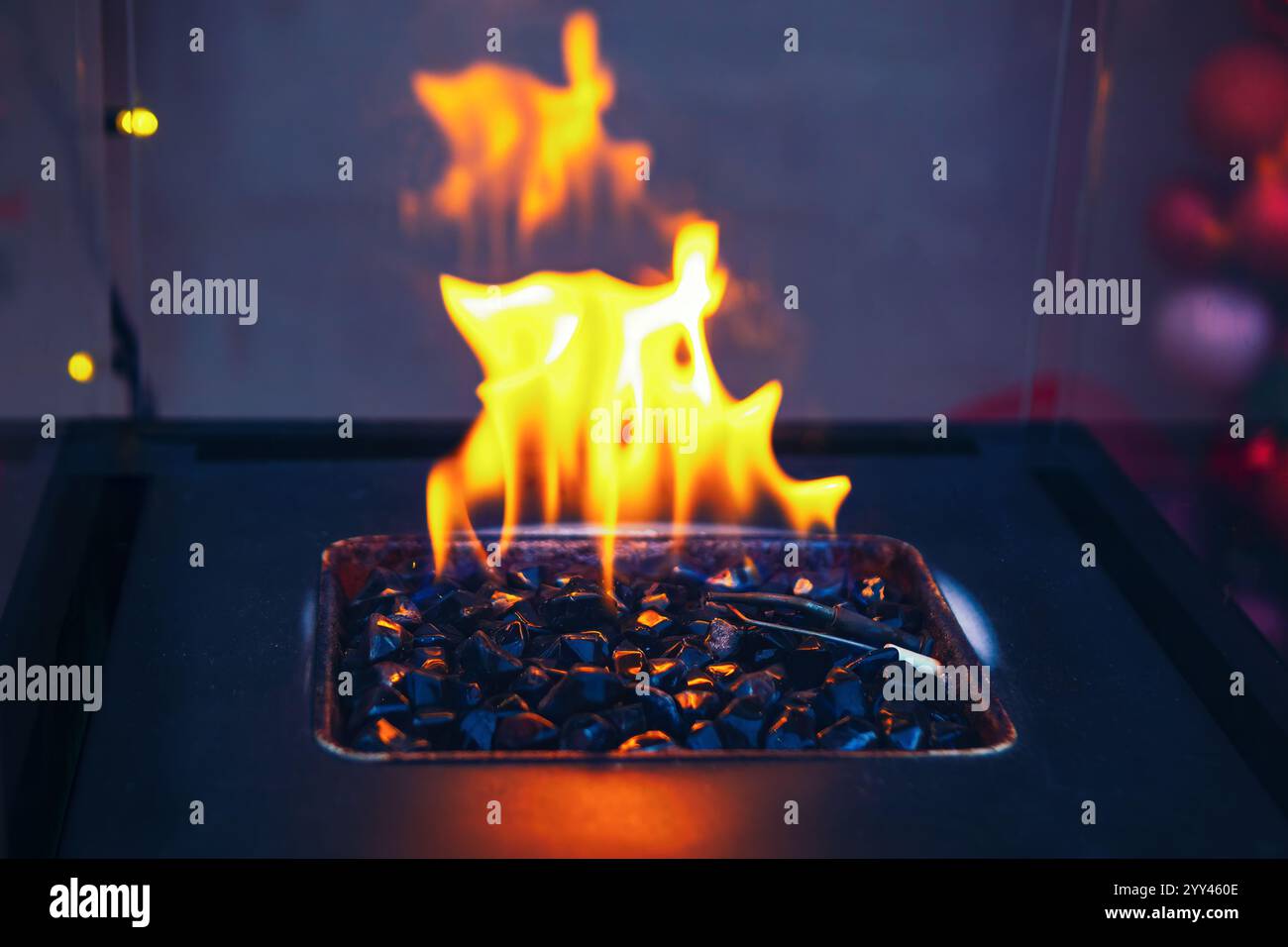 View of a modern fire pit with a visible flame burning over a bed of ...