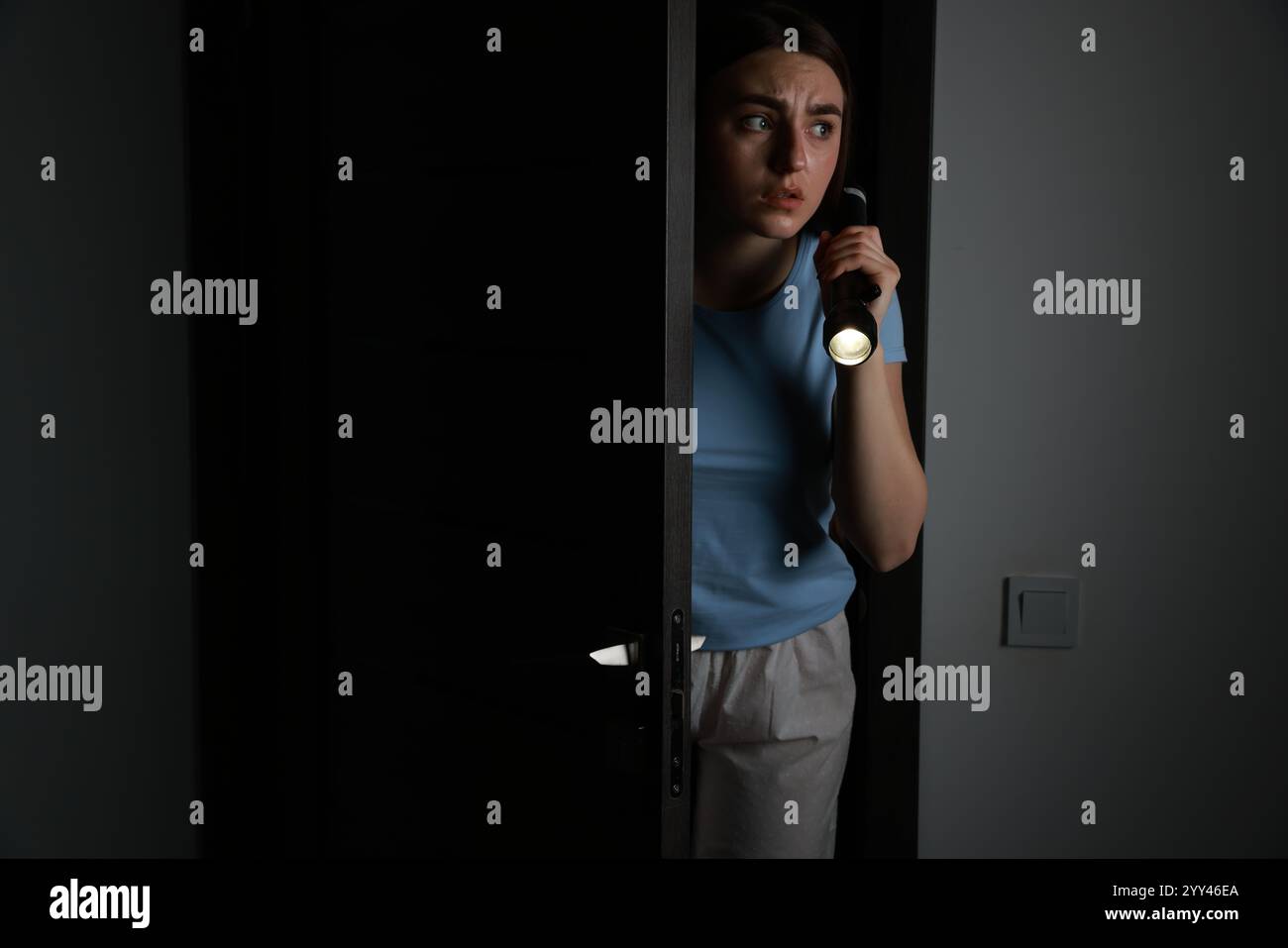 Fear of darkness. Scared young woman with flashlight indoors at night ...