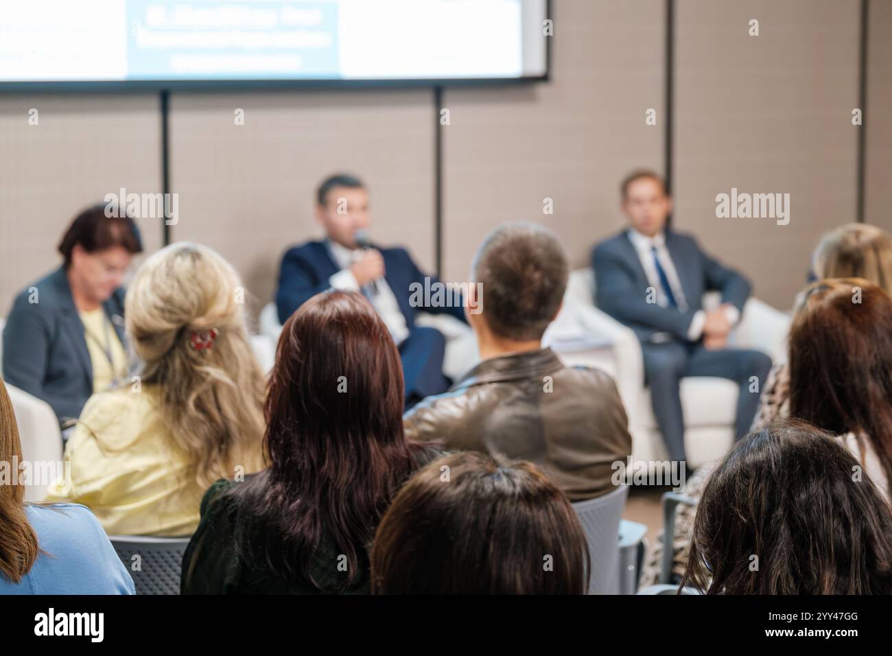 Attendees seated and listening to a panel discussion with corporate ...