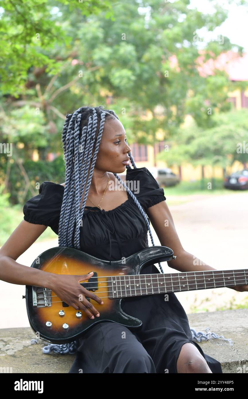 Image of young black african woman playing acoustic guitar outdoor ...