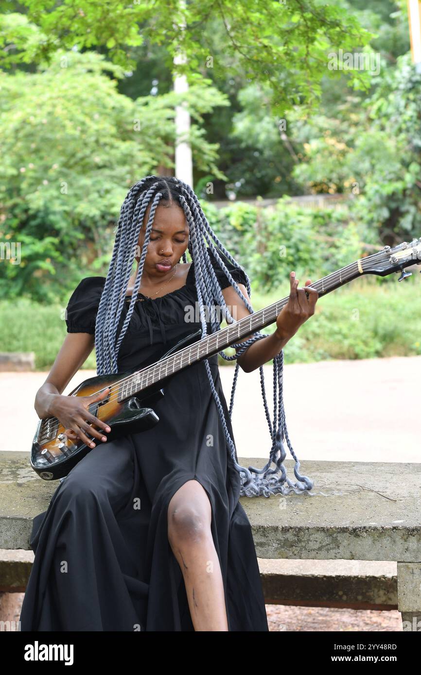 Image of young black african woman playing acoustic guitar outdoor ...