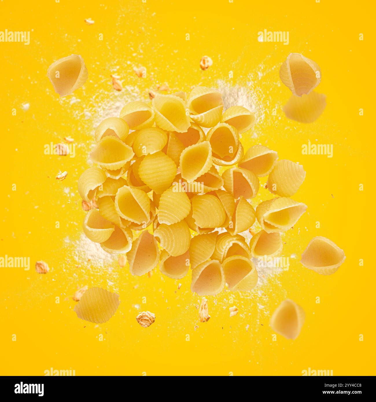 Conchiglie pasta shells exploding on vibrant yellow background Stock ...