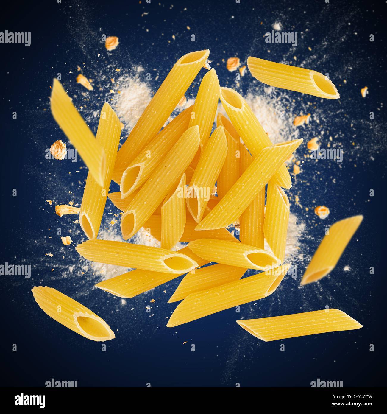 Raw penne rigate pasta is flying on a blue background, accompanied by ...