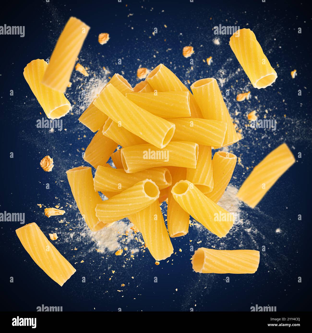 Uncooked tortiglioni pasta exploding on a blue background, creating a ...