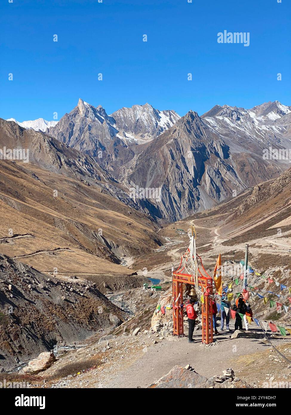 Sacred gate with flags and temple bell on the road leading to Om Parvat ...