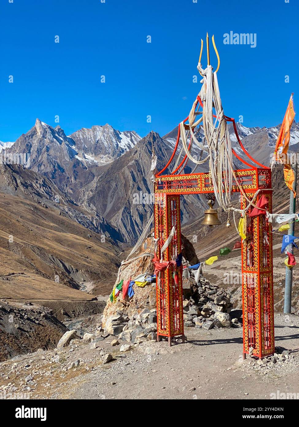 Sacred gate with flags and temple bell on the road leading to Om Parvat ...
