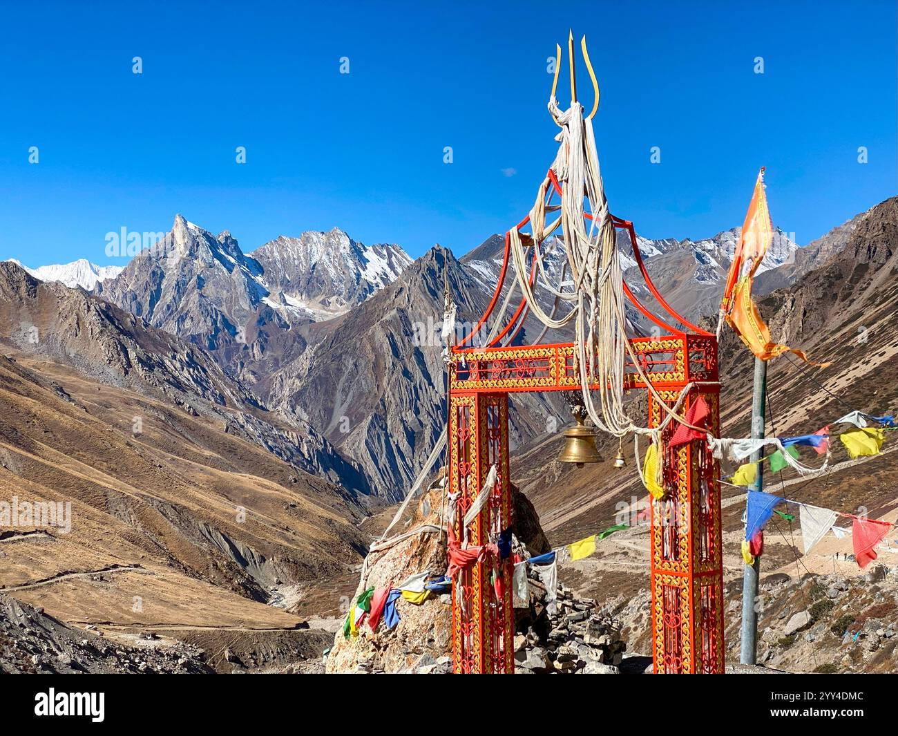 Sacred gate with flags and temple bell on the road leading to Om Parvat ...