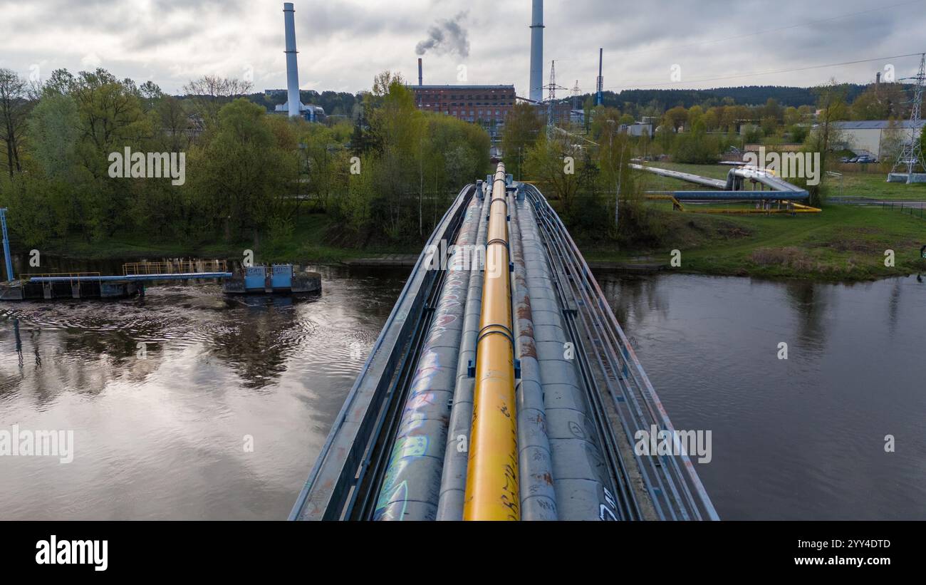 Industrial pipes crossing a river with a factory in the background ...