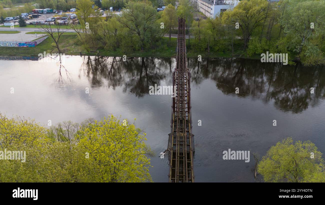 An old industrial pipe bridge crossing a river, surrounded by lush ...
