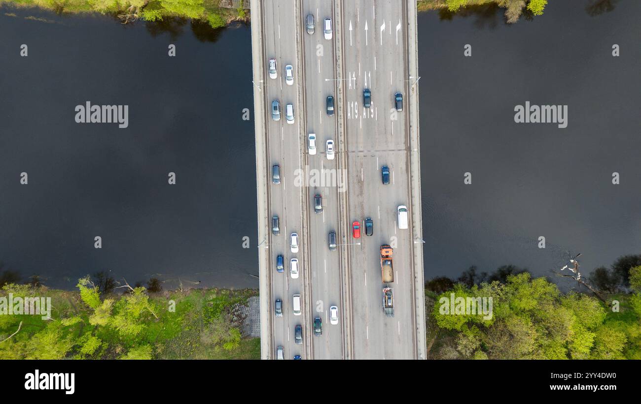 Aerial view of a busy highway bridge over a river with green trees on ...