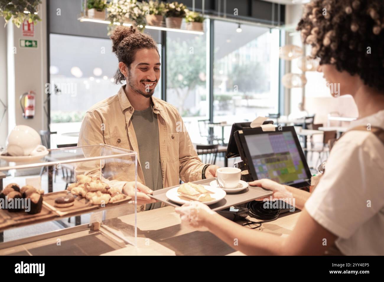 A cheerful cafe worker serves a customer with coffee and pastry The ...