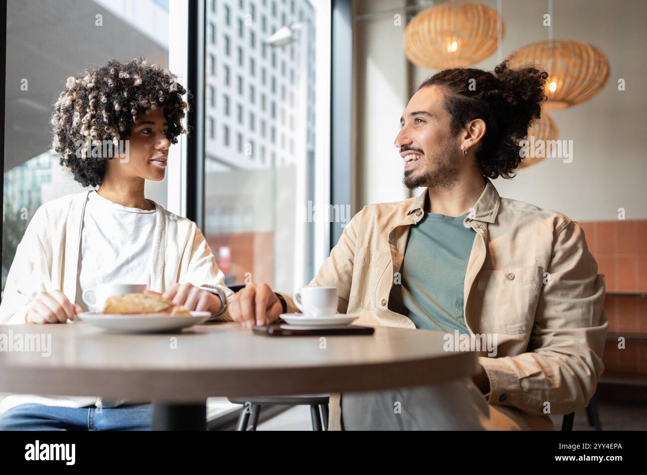 Two friends enjoy a relaxed conversation in a modern cafe They sit at a ...