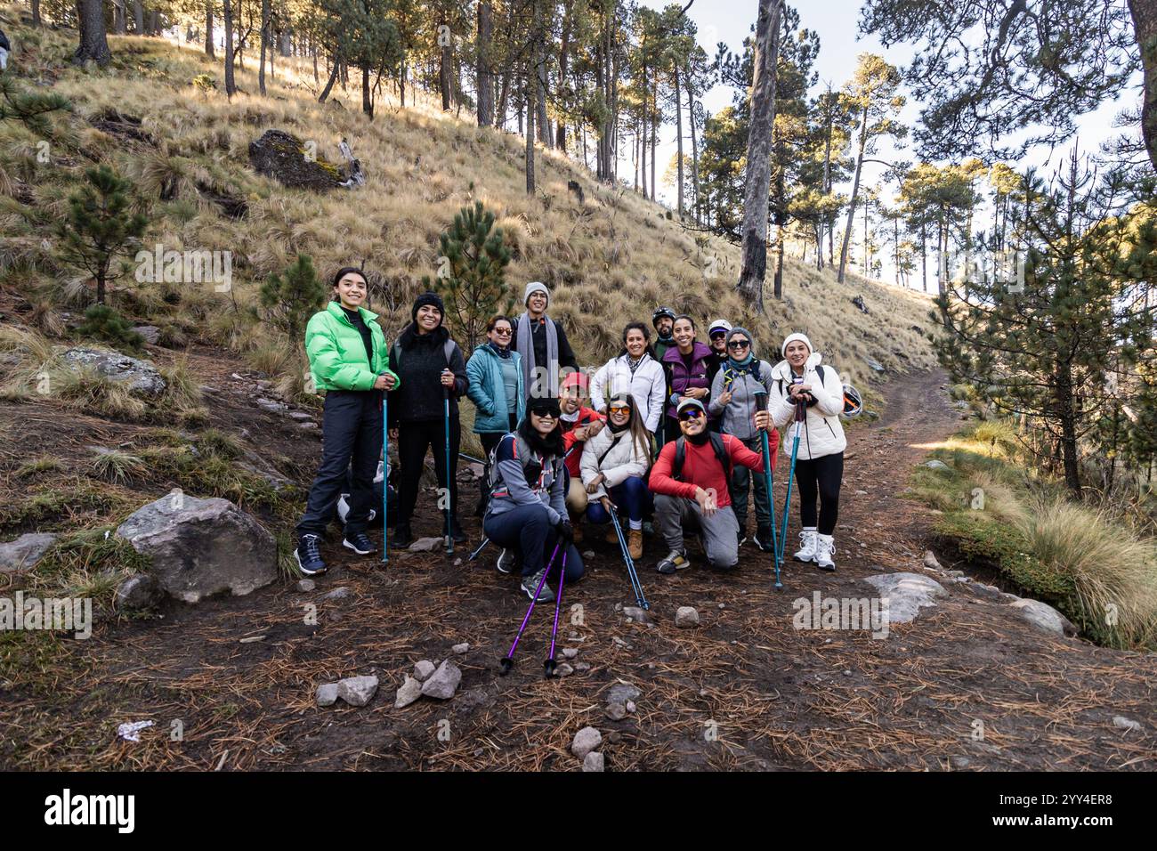 A cheerful group of hikers, equipped with trekking poles, poses ...