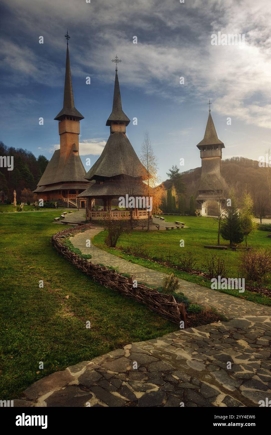 Serene sunrise illuminating historic wooden churches in Sapanta, Romania, set against lush ...