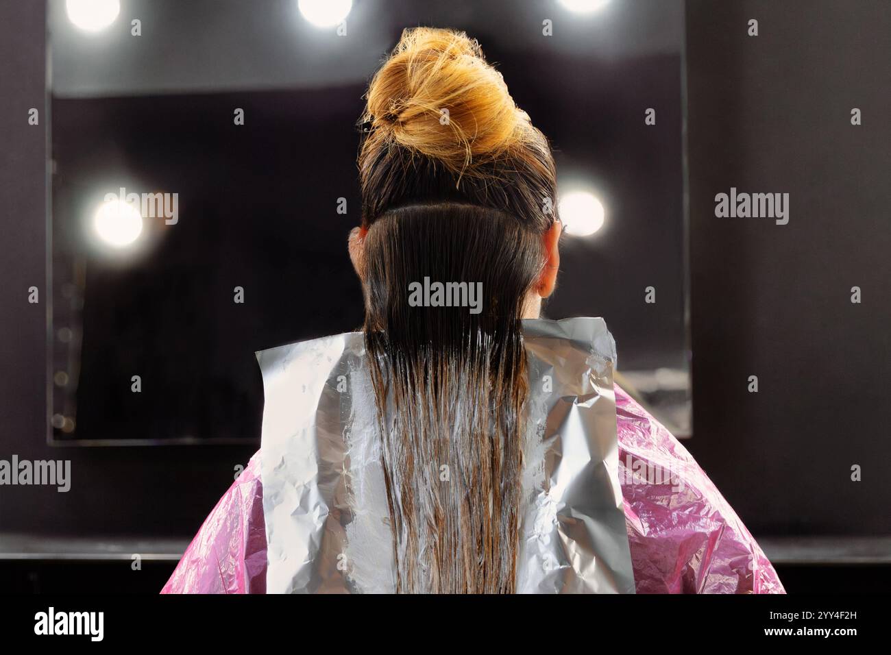 A woman receives hair coloring treatment in a salon Hair is sectioned ...