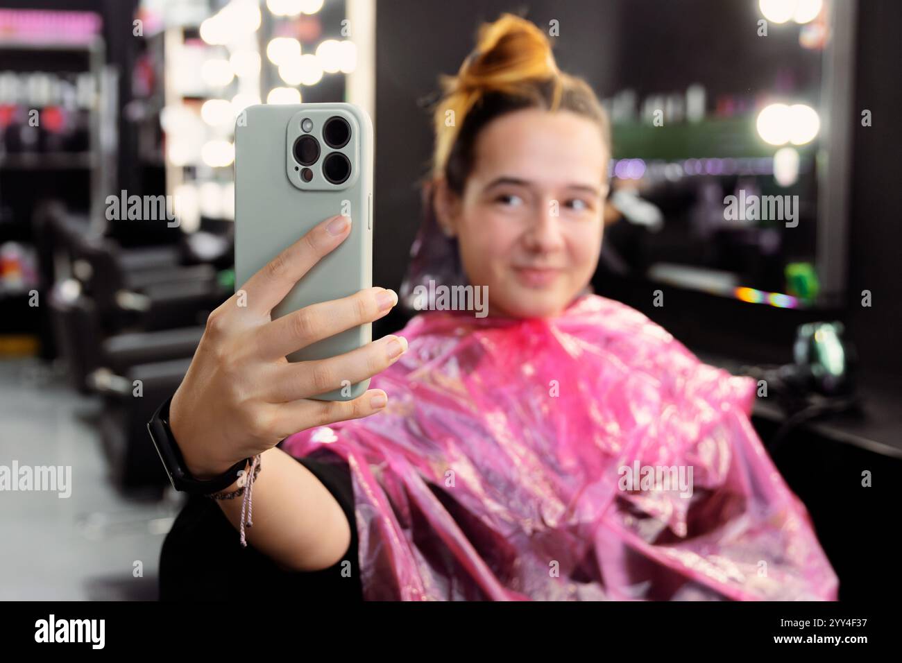 A person in a hair salon captures a selfie during a hair styling ...