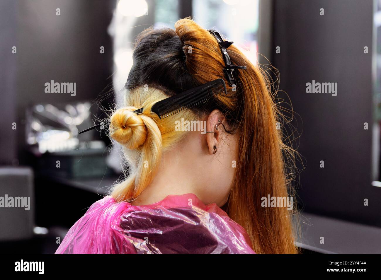A close-up of a client’s hair being styled in a salon, featuring a comb ...