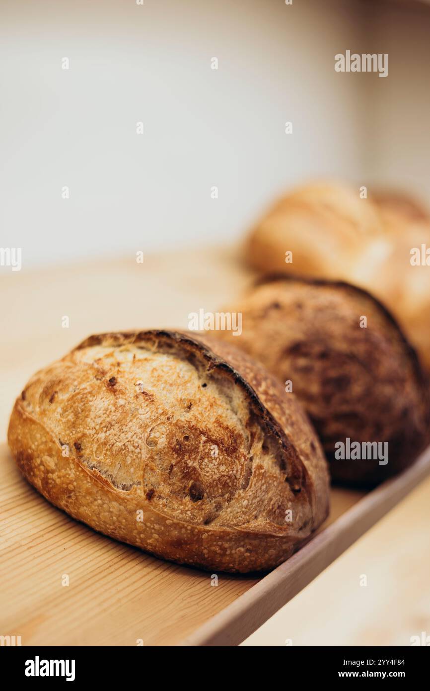 Close-up of freshly baked artisan bread resting on a rustic wooden ...