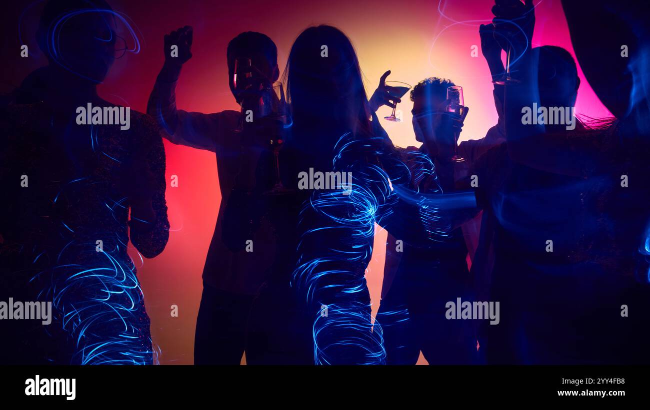 Friends raise glasses high, celebrating holidays in neon lights, dance ...