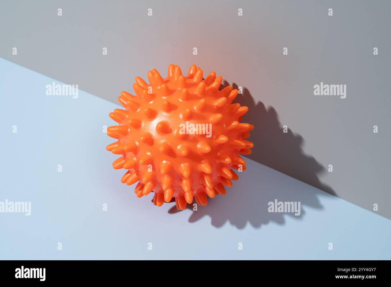 An orange spiky massage ball sits on a two-tone background. Ideal for ...
