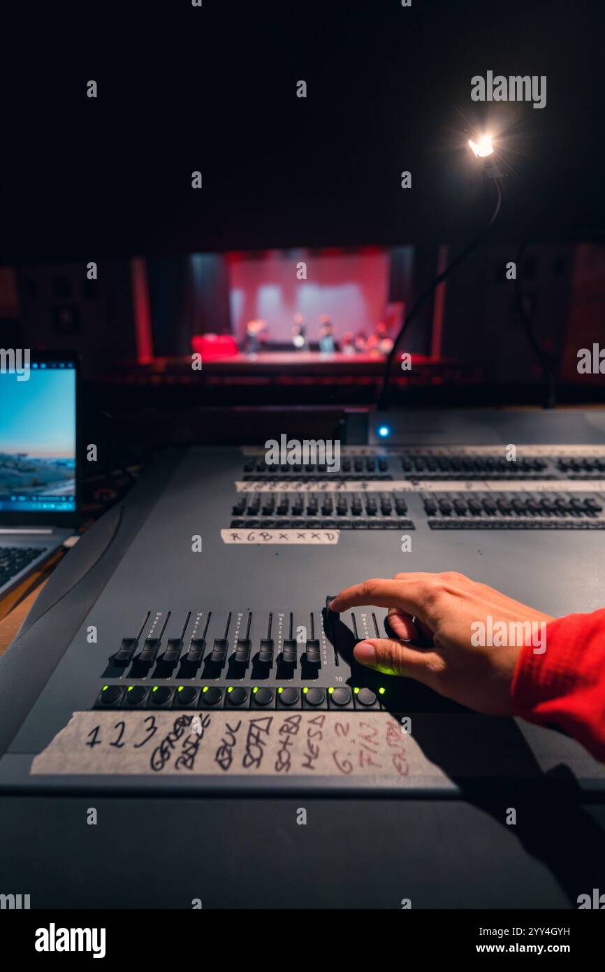 A sound engineer in a theater booth adjusts a control panel during a ...