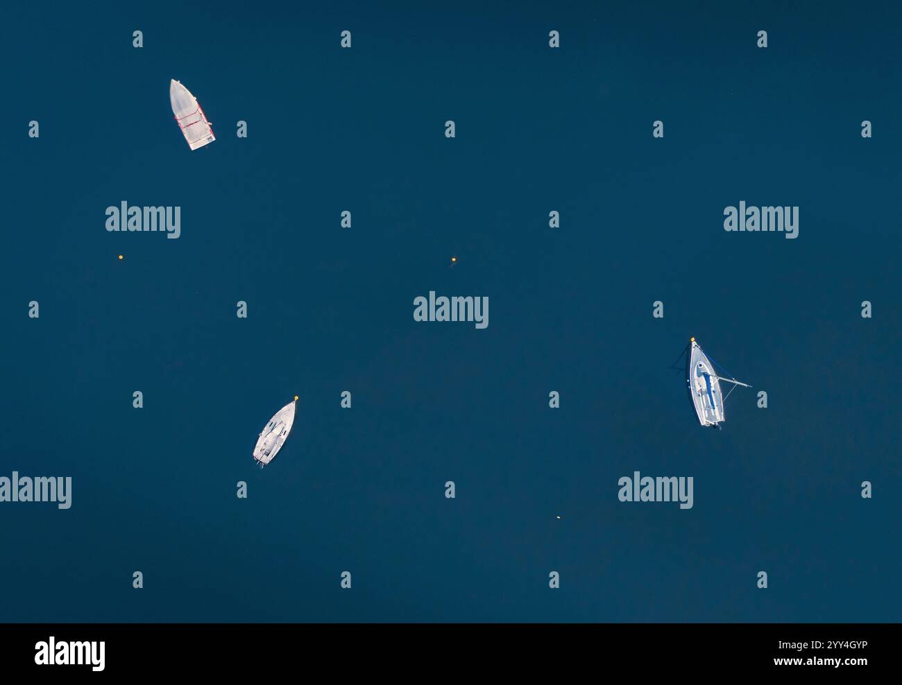Aerial perspective captures three white boats peacefully anchored in ...