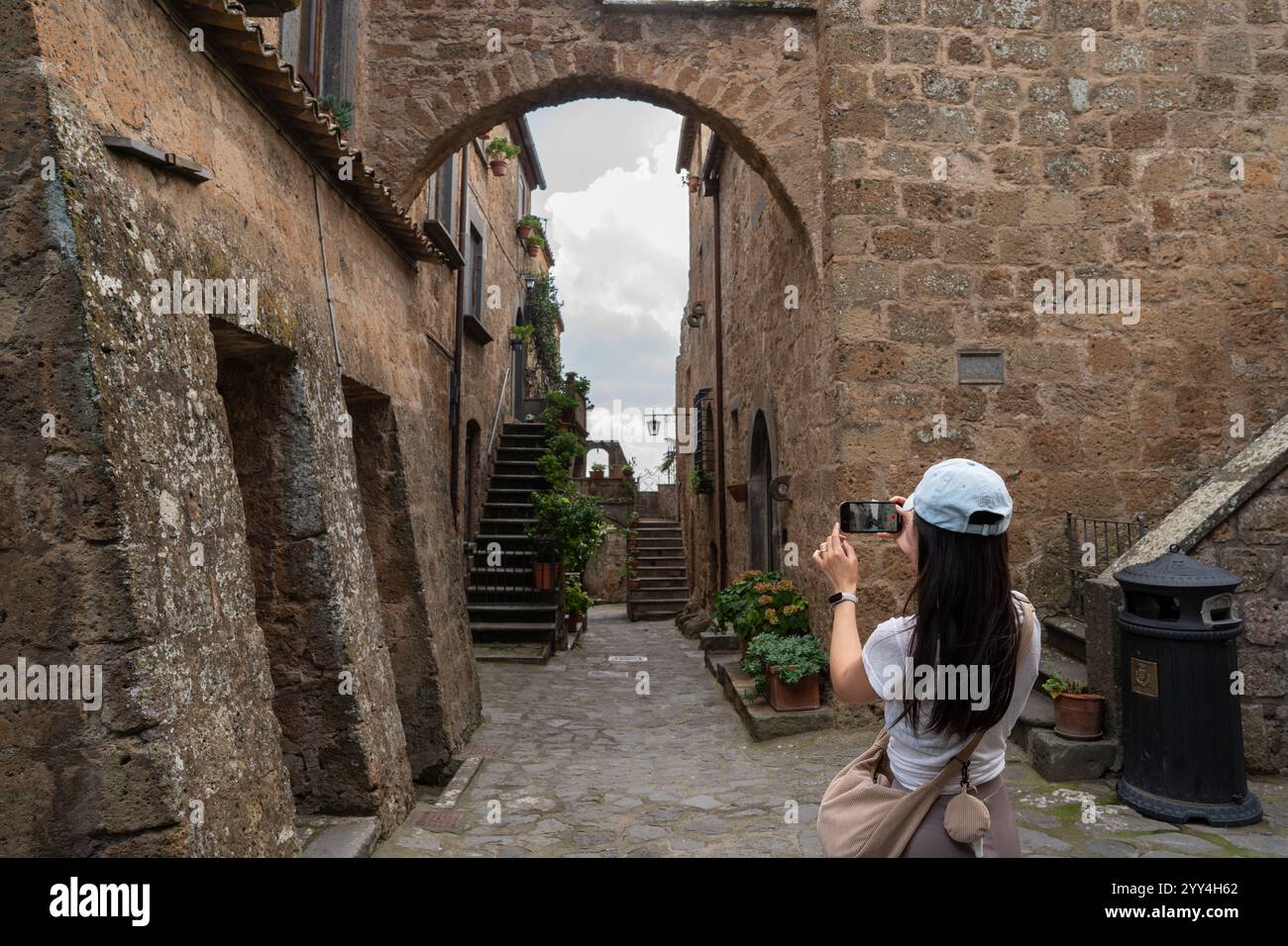 A tourist captures an ancient cobblestone street and archway with a ...