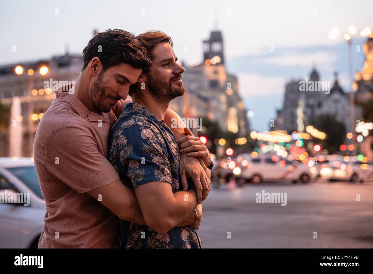 A tender moment between two men as one embraces the other from behind ...
