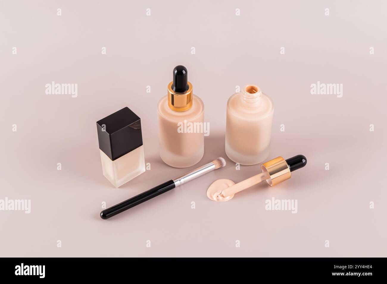 Aesthetic display of three foundation bottles and a makeup brush on a ...