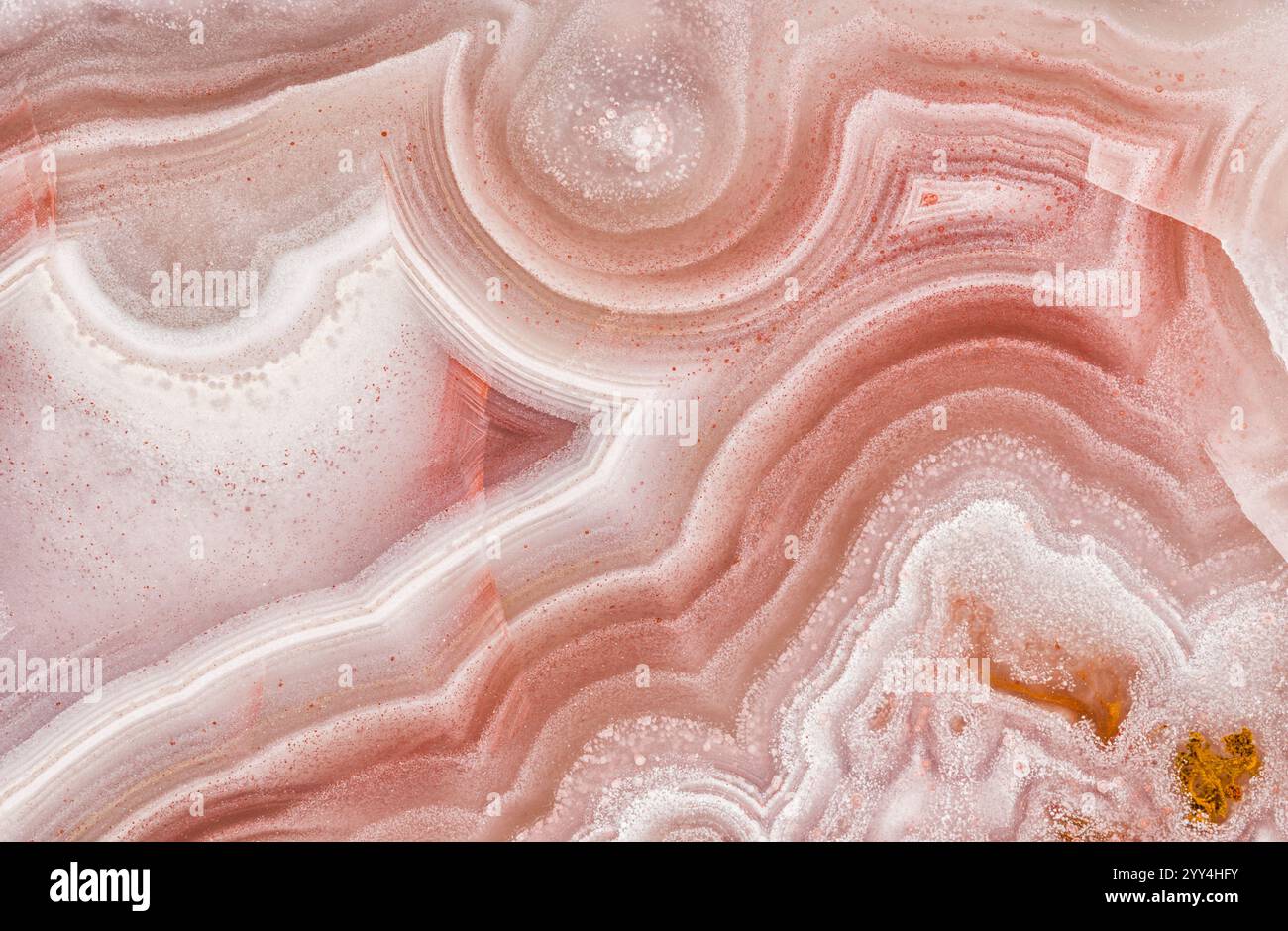 Close-up image of an agate stone reveals swirling layers of pink and ...