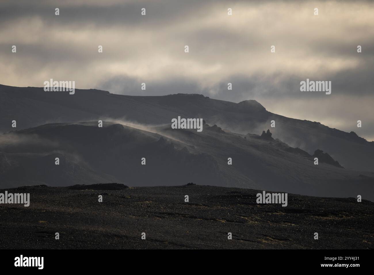 A dramatic Icelandic landscape features rugged hills under a heavy ...