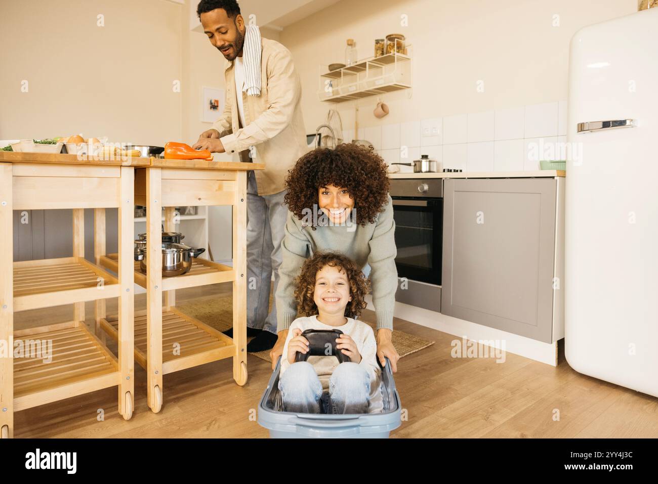 A joyful family scene with father cooking and mother playing with a ...