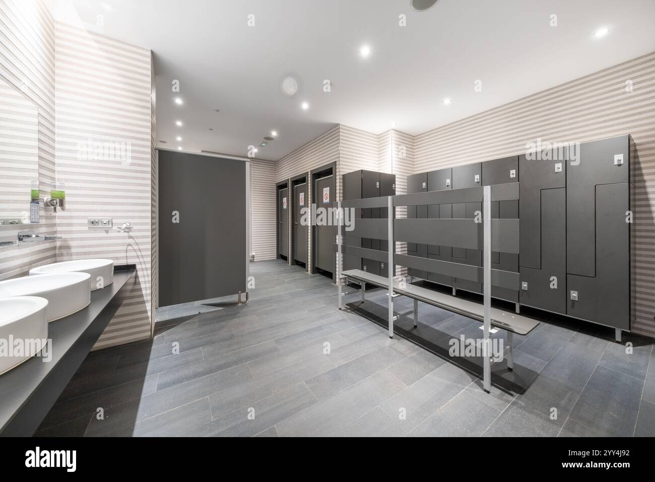 A contemporary spa changing room features sleek lockers, modern sinks ...