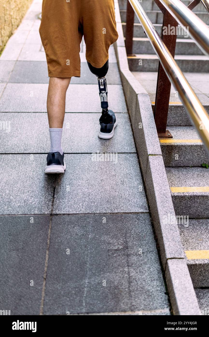 A man with a prosthetic leg climbs concrete steps outdoors, showing ...