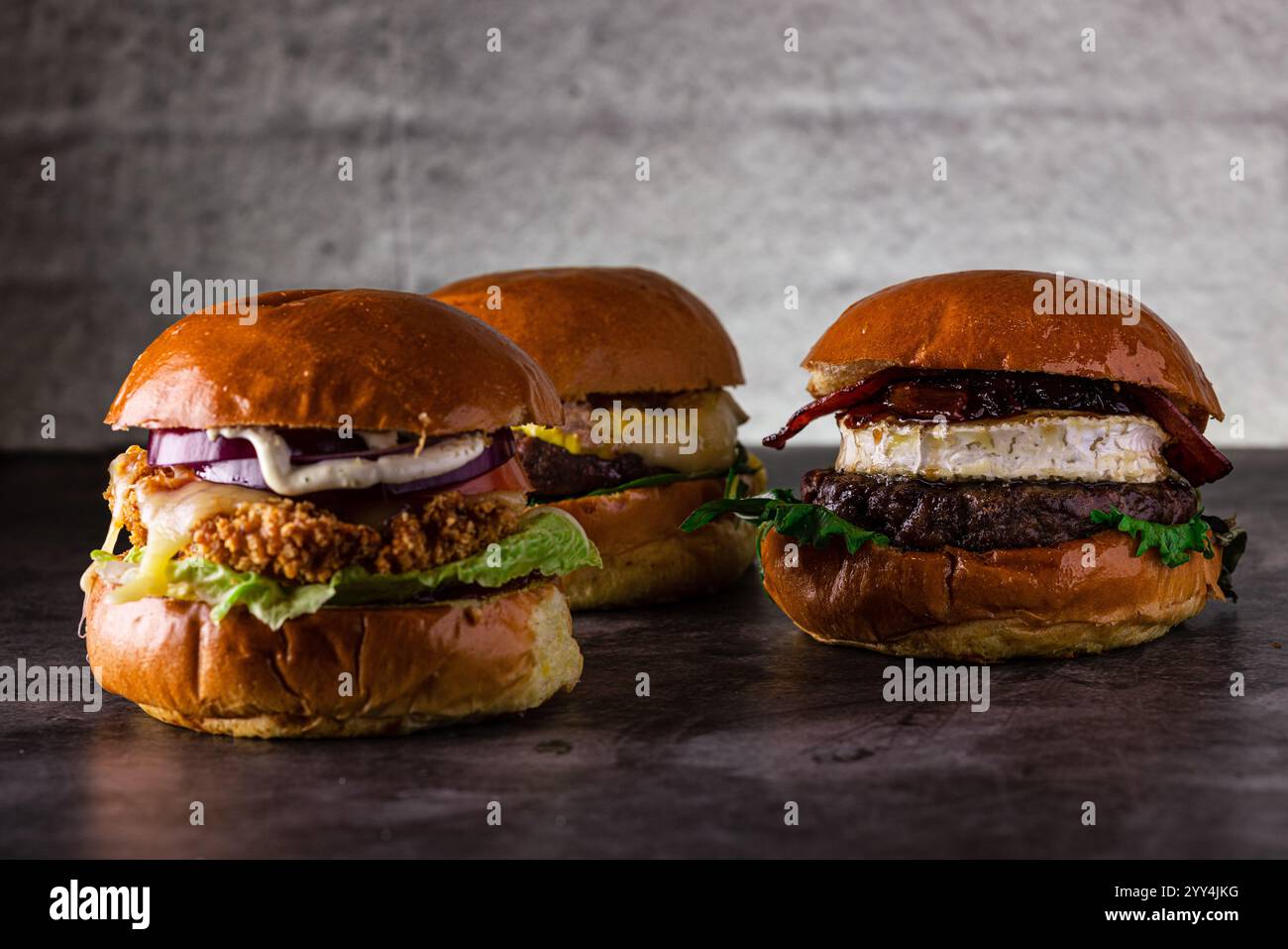 Three gourmet burgers with juicy patties, melted cheese, onions, crisp ...