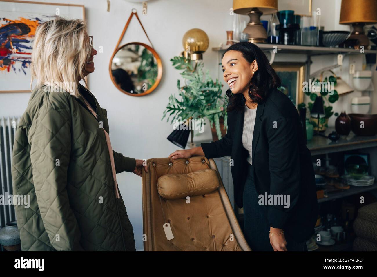 Happy female owner talking with customer buying furniture at antique ...