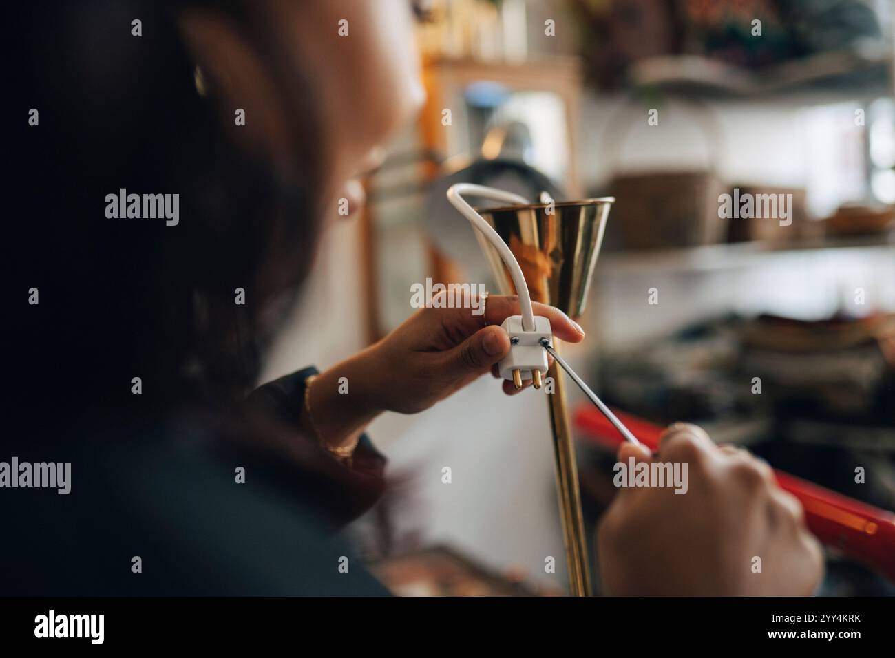Female entrepreneur repairing electric socket at antique store Stock ...