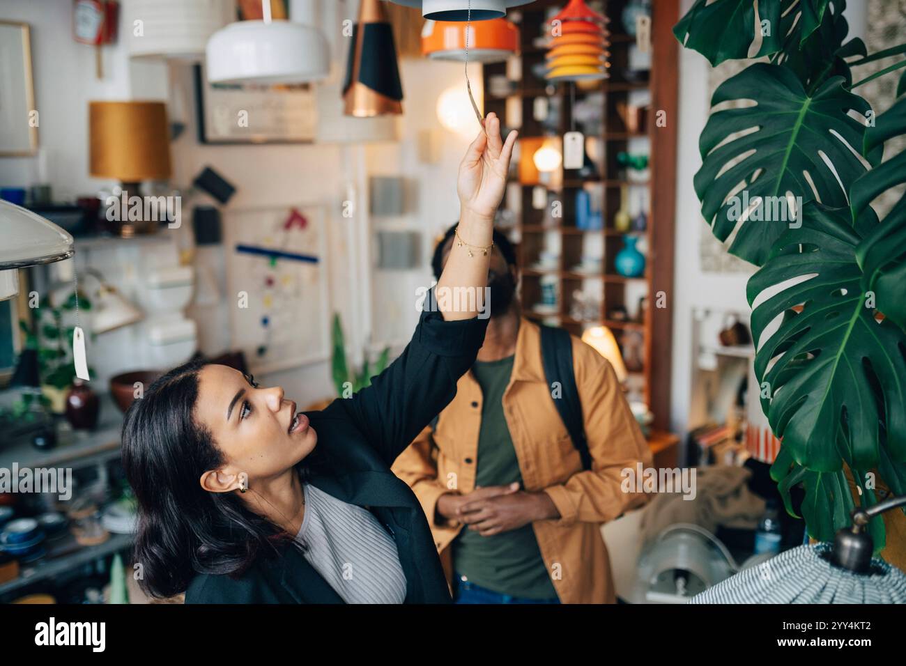 Female owner reading price tag for customer doing shopping at antique ...