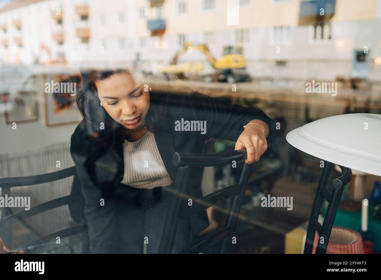 Female store owner arranging furniture seen through glass window Stock ...