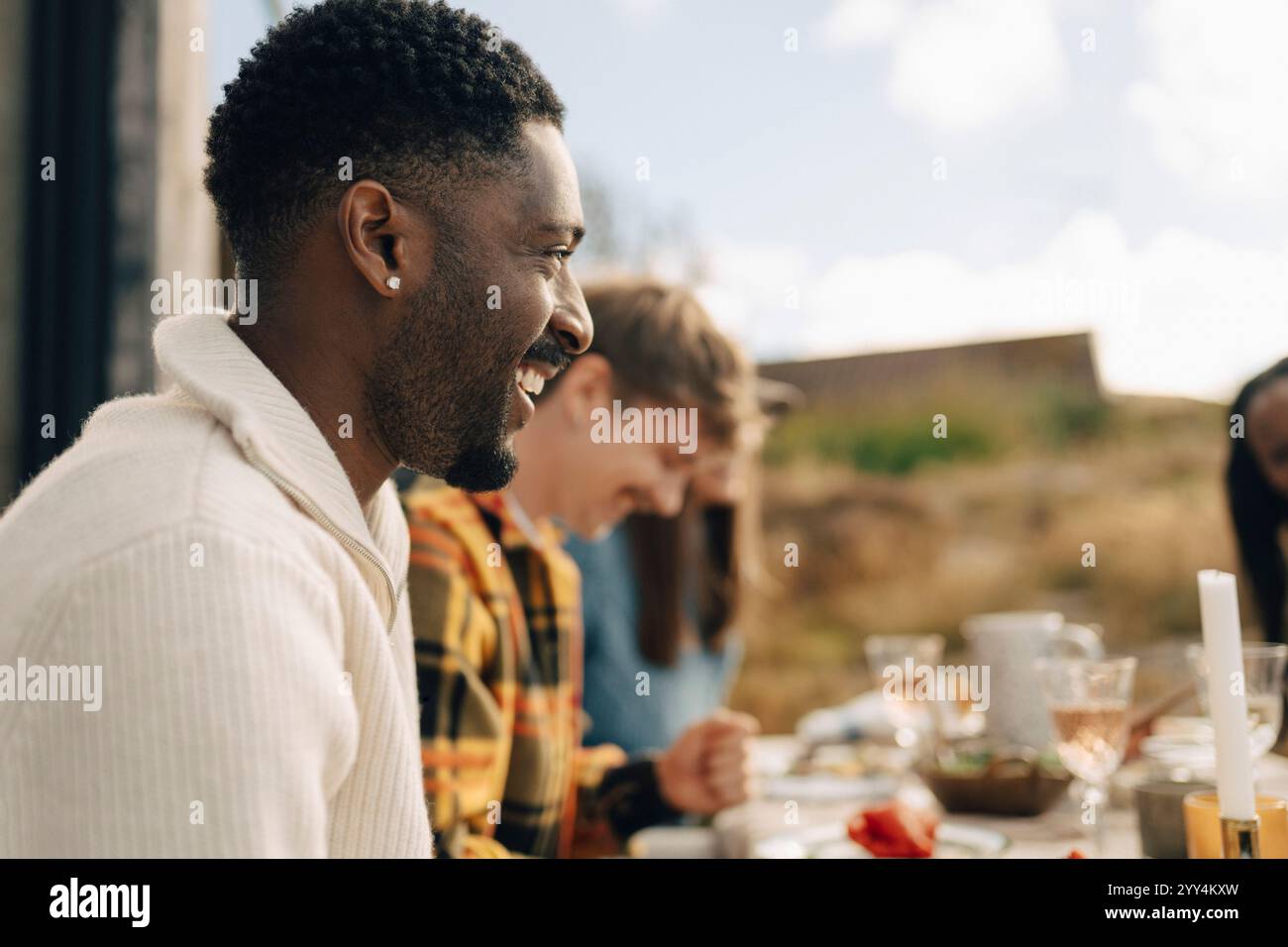 Side view of happy man having dinner with friends at outdoor setting ...