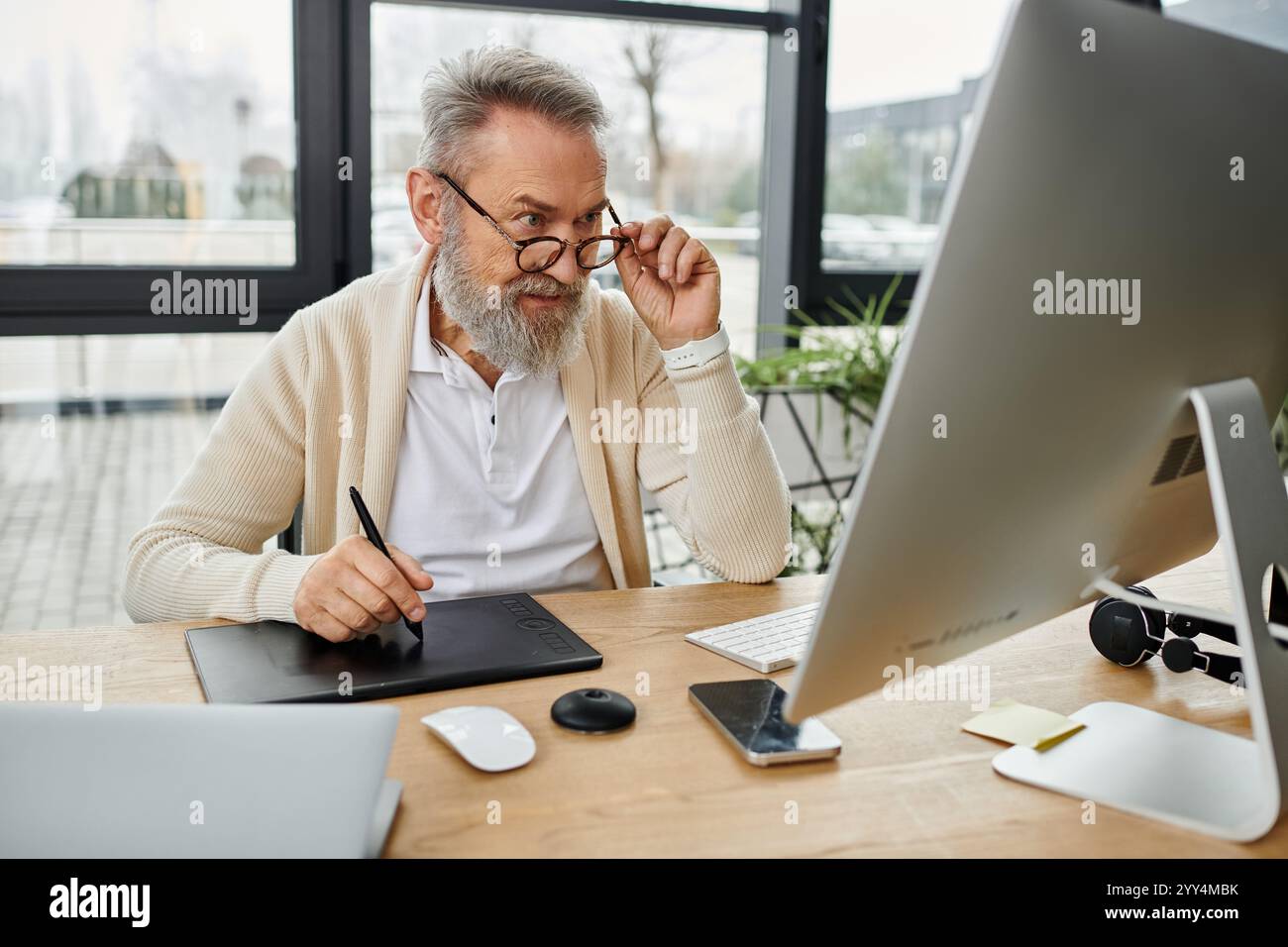 A mature handsome man is focused on his tasks at a sleek workspace with ...