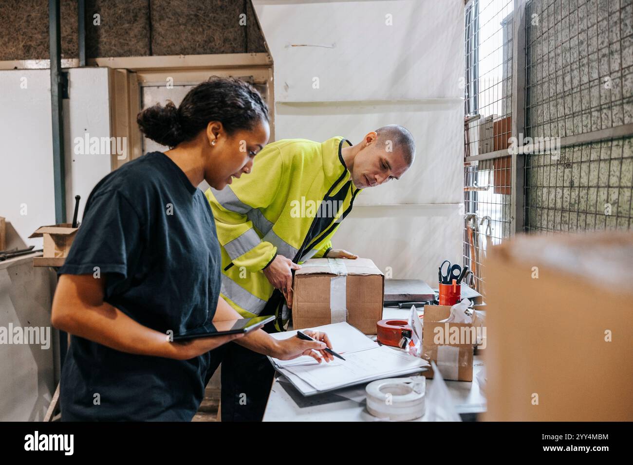 Female employee taking inventory with male colleague in distribution ...