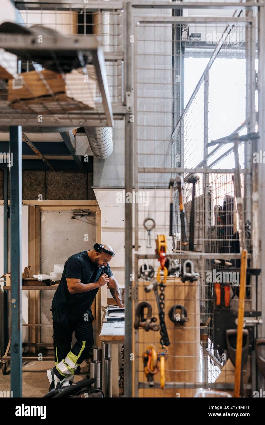 Concentrated mature employee standing with legs crossed at ankle near ...