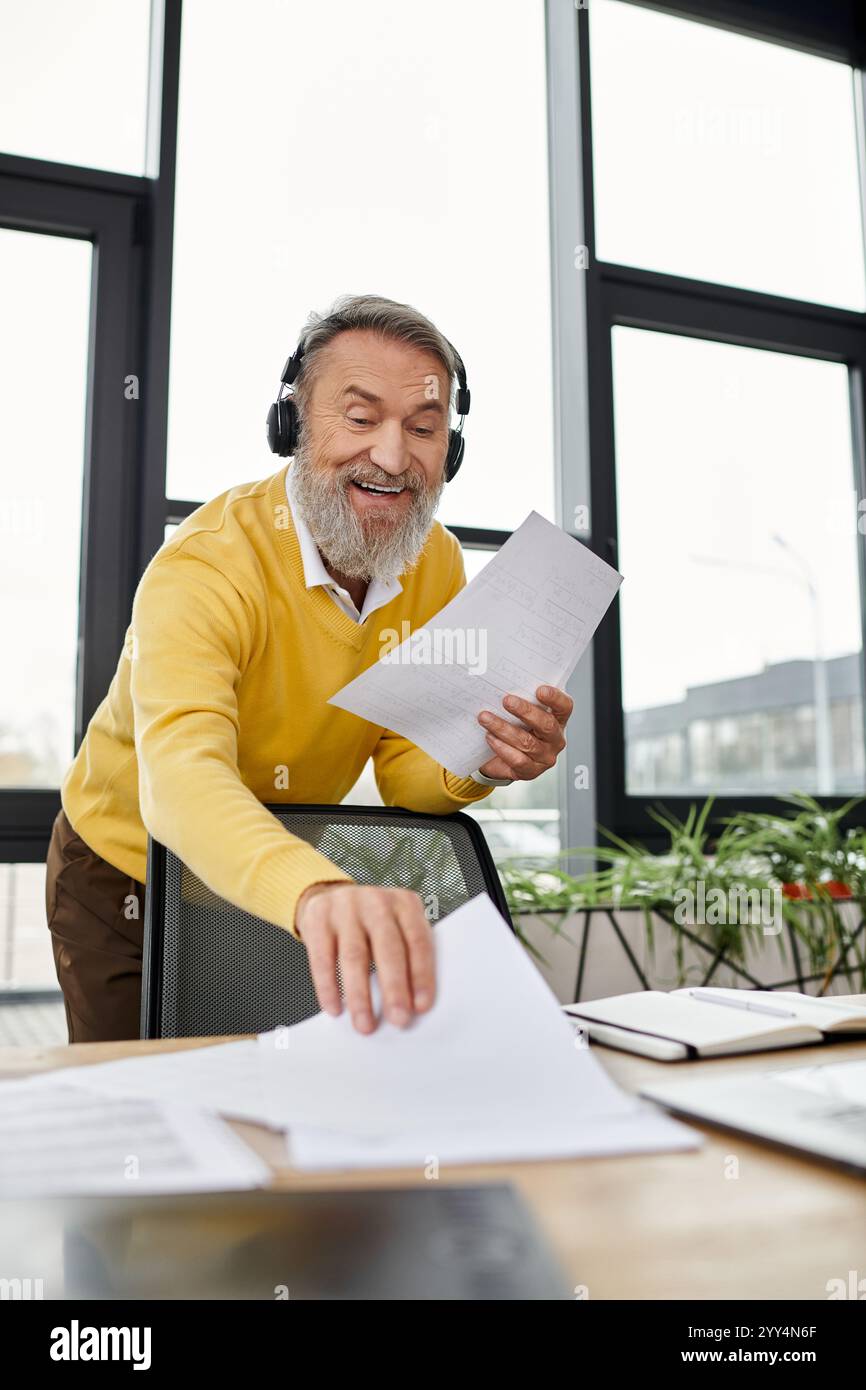 Senior man engages with papers at his desk, displaying joy and ...