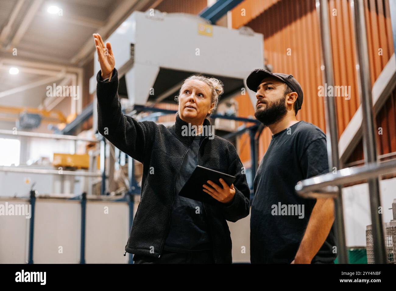 Mature woman discussing with male coworker standing in distribution ...