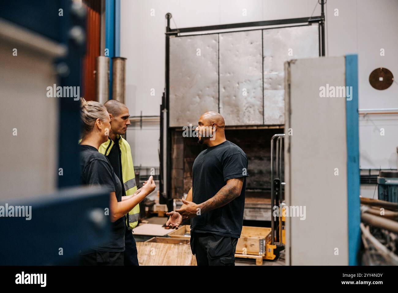 Bald worker discussing with female and male colleague at distribution ...
