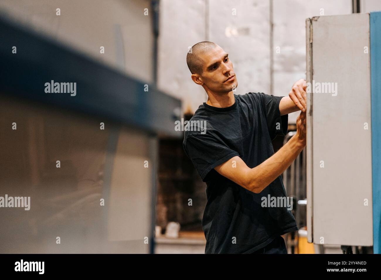 Shaved head male worker working in manufacturing industry Stock Photo ...