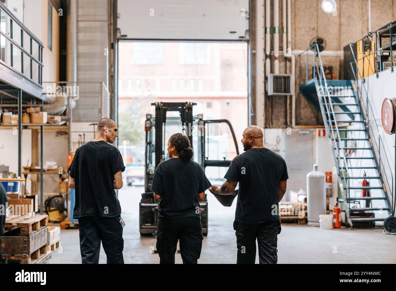 Rear view of male and female manufacturing professional discussing with ...